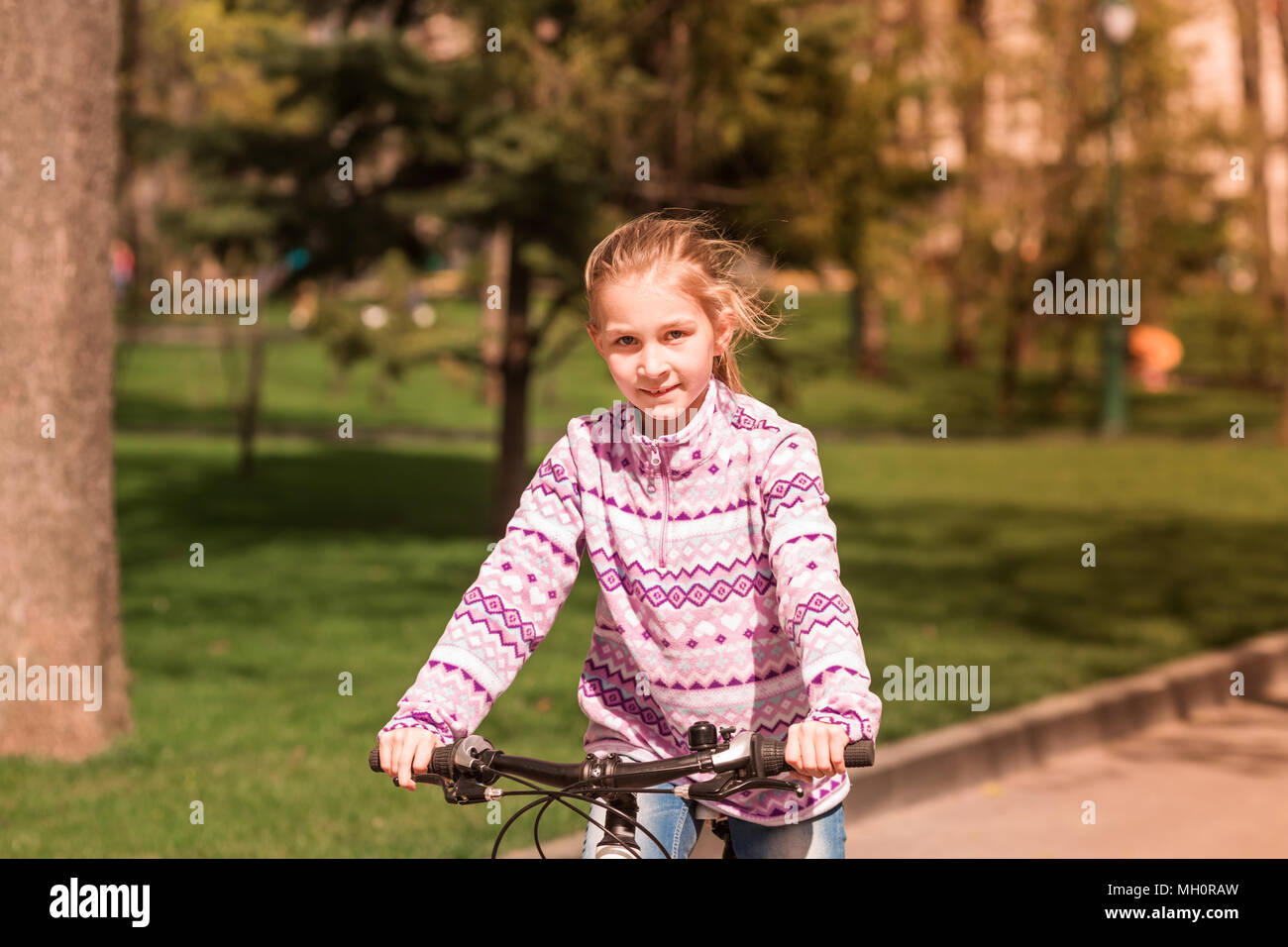Happy little girl riding a bike in the park Stock Photo - Alamy