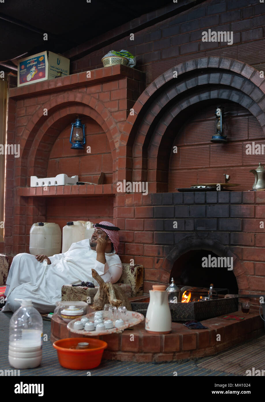 Saudi man resting in a chalet near a fireplace, Najran Province, Najran ...