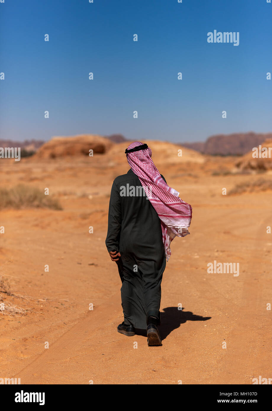 Rear view of a saudi man walking in the desert, Al Madinah Province, Al ...