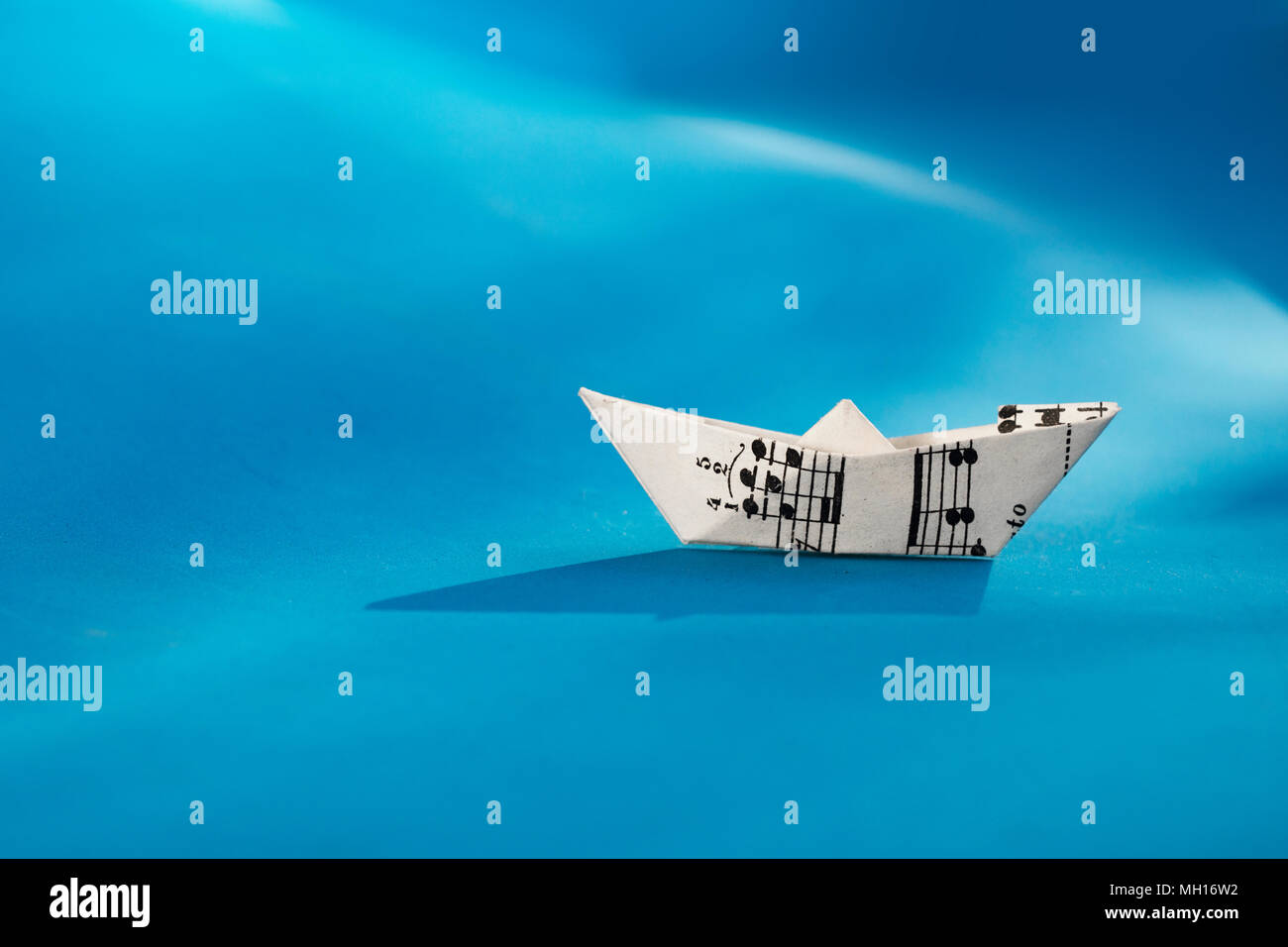 Paper boat made of musical score sheet in blue background Stock Photo ...