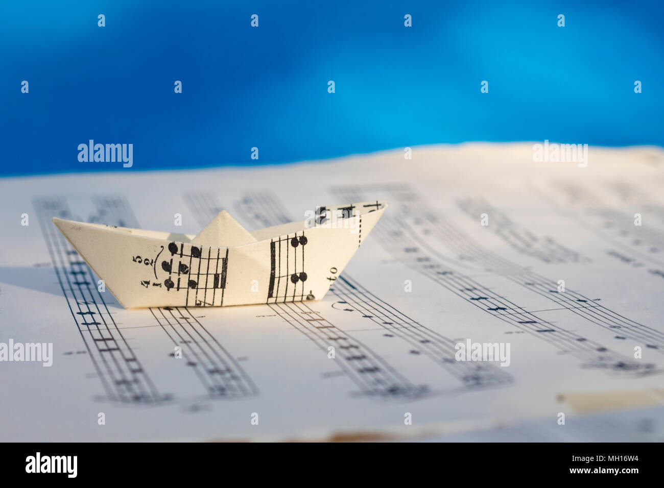 Paper boat made of musical score sheet in blue background Stock Photo ...