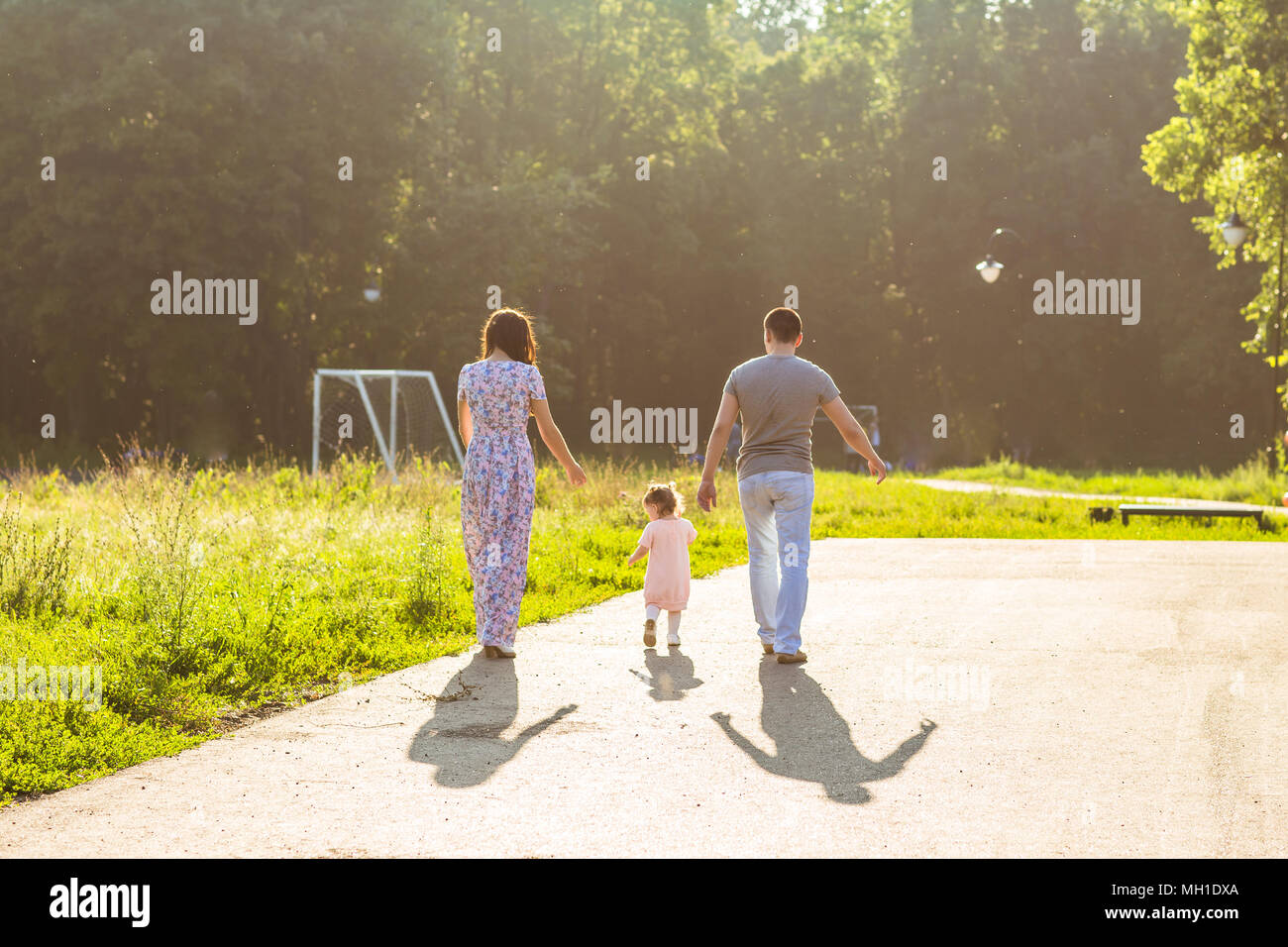 Happy family outdoor activity. Rear view of parents and baby daughter ...