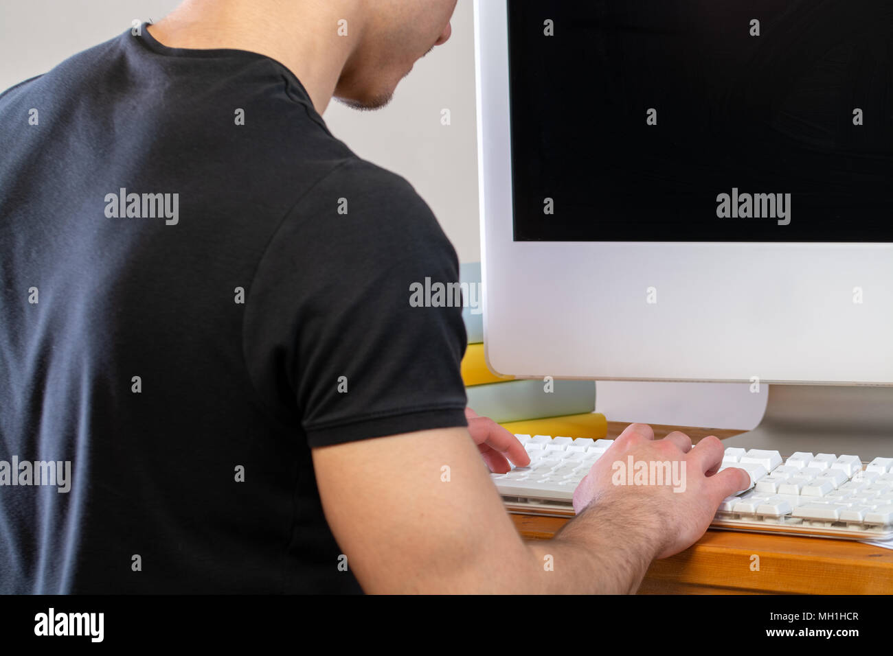 a young man with black tshirt working on the computer Stock Photo - Alamy