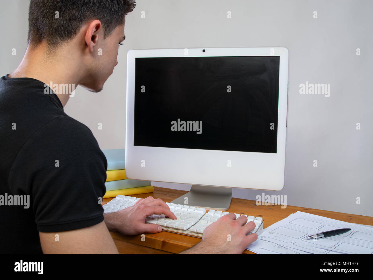 a young man with black tshirt working on the computer Stock Photo - Alamy