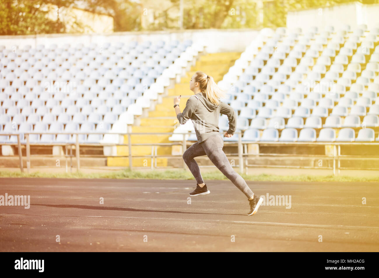 Portrait of a young woman running at the stadium outdoors Stock Photo ...