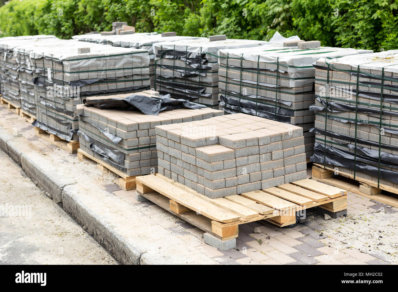 Row of stacks of gray pavement slab on wooden base. Concrete stone ...