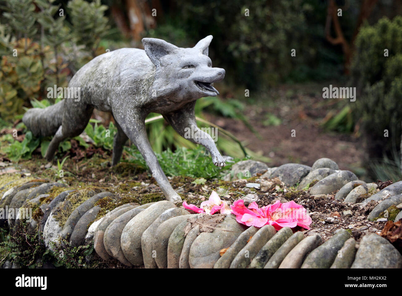 A stone statue of a fox on the top of a stone wall in the middle of a ...