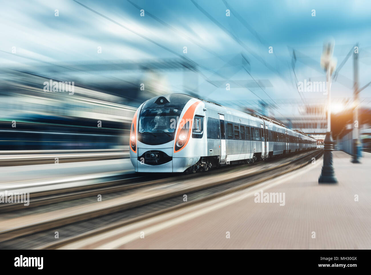 High speed passenger train in motion on the railway station at sunset ...