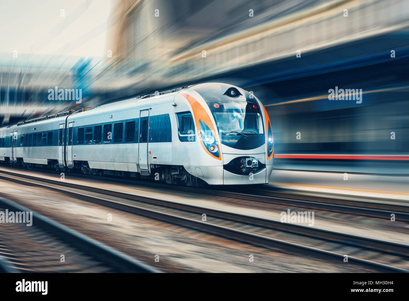 High speed passenger train in motion on the railway station at sunset ...
