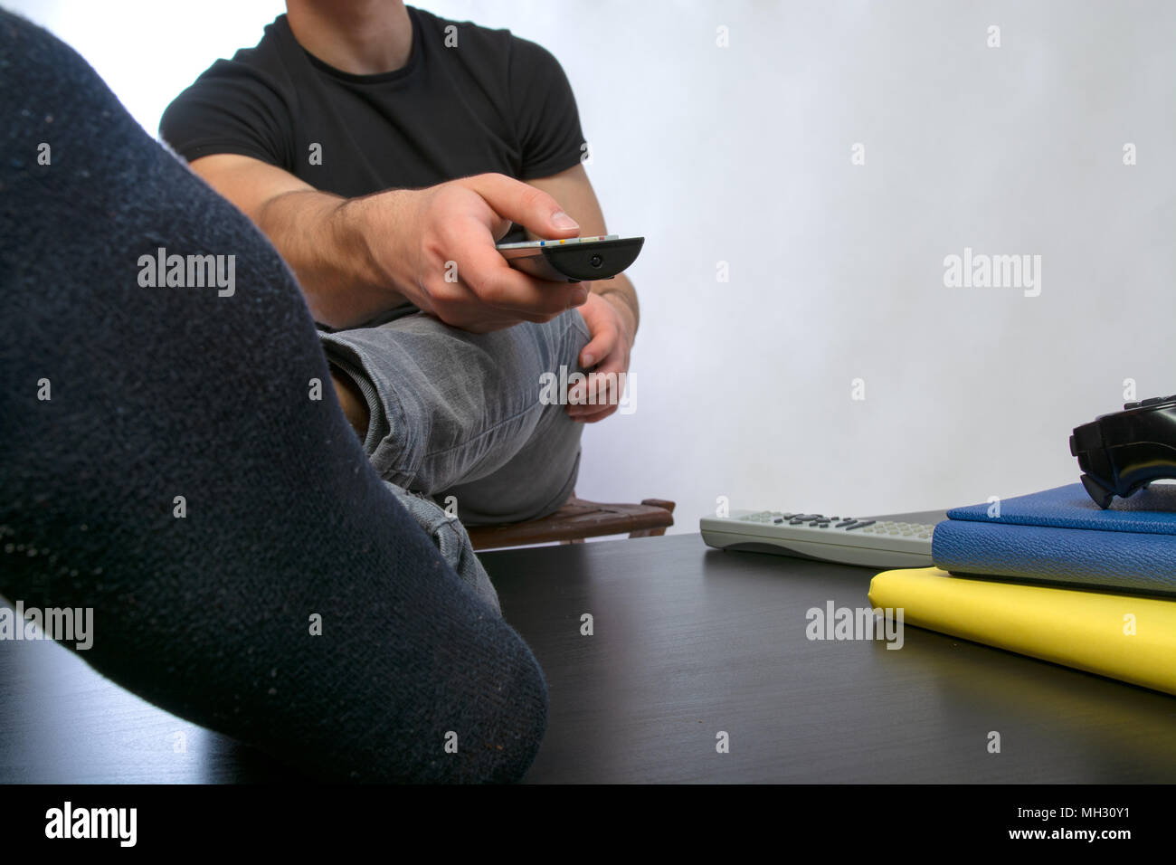 a young man with black changing the channel of the tv, relaxing Stock ...