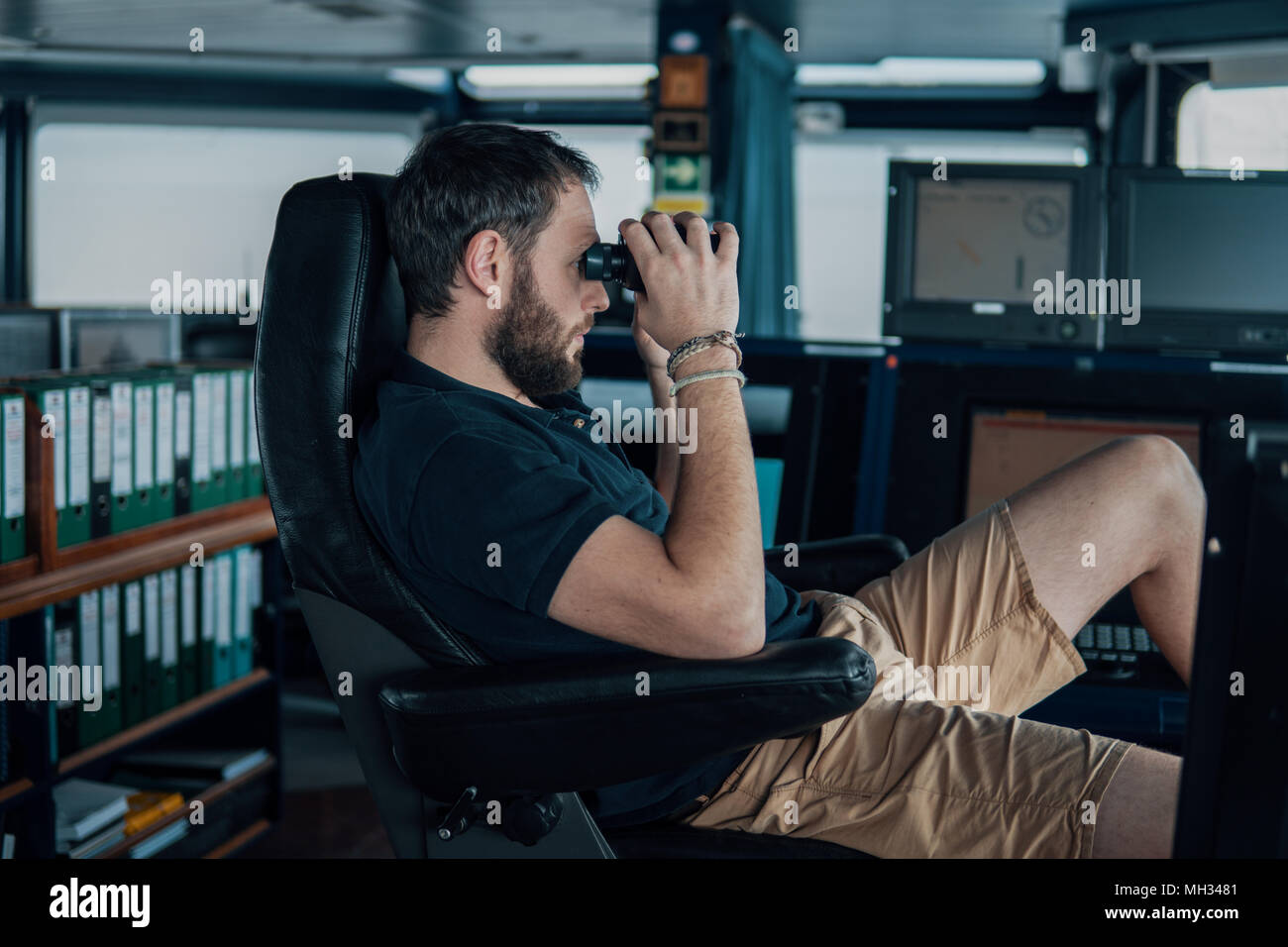 Deck navigation officer on the navigation bridge. He looks through ...