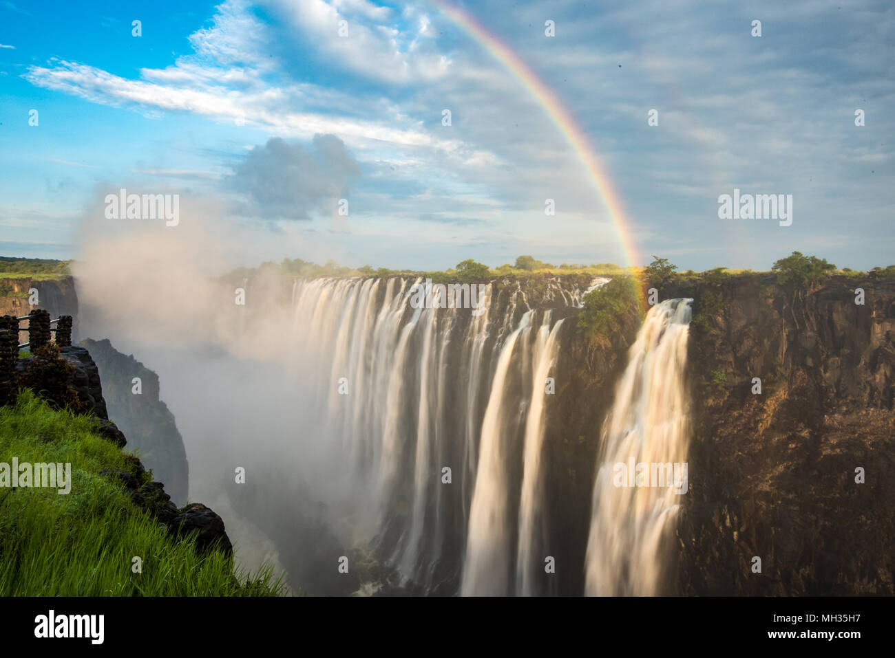 The rushing waters of Victoria Falls spray mist into the air creating a ...