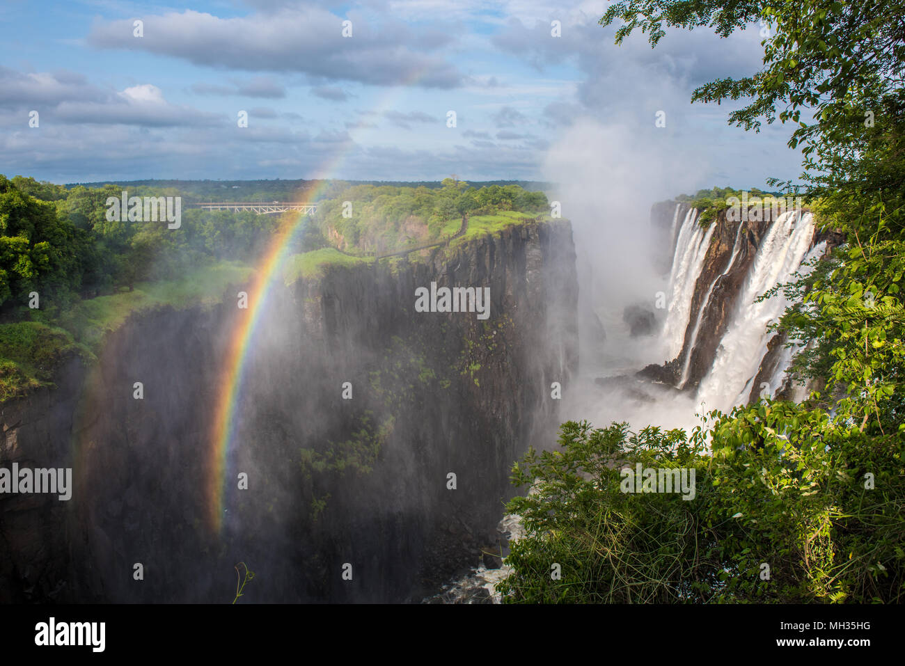 The rushing waters of Victoria Falls spray mist into the air creating a ...