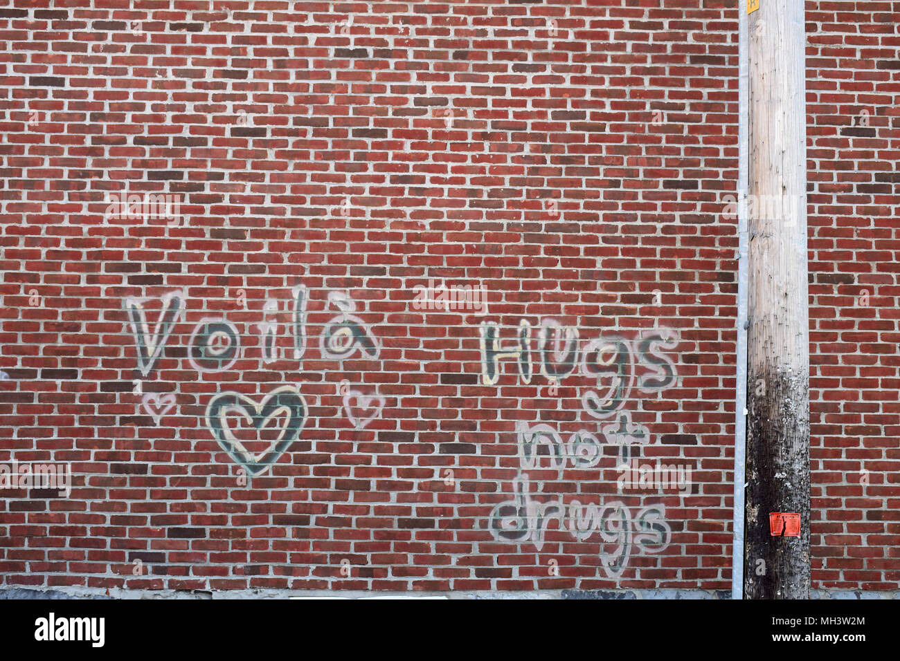 A brick wall with a painted heart and the words hugs not drugs Stock ...