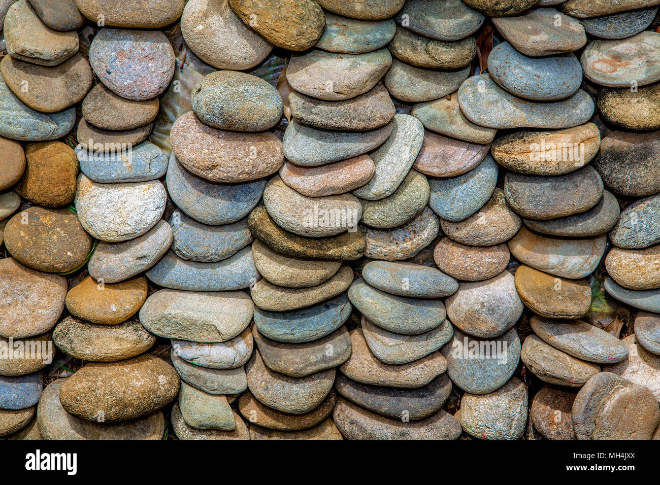 Overlapping, small, multi-coloured river stones are used as a ground ...
