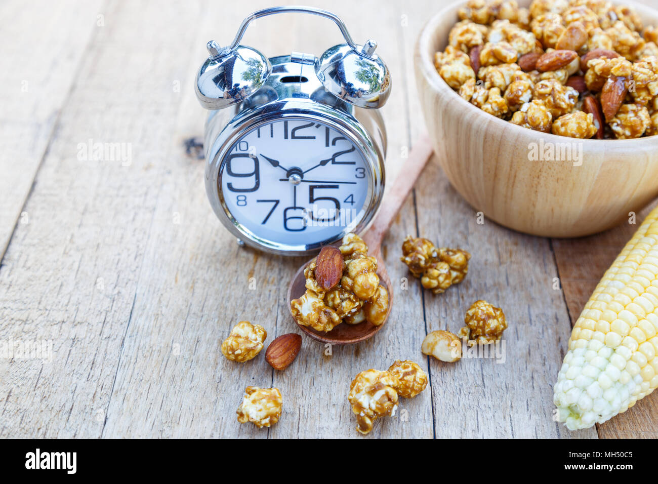Popcorn caramel mix macadamia and almond taste and alarm clock on wood ...