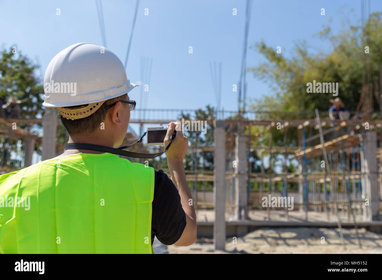 Engineers wear a helmet and holding construction plan and camera ...