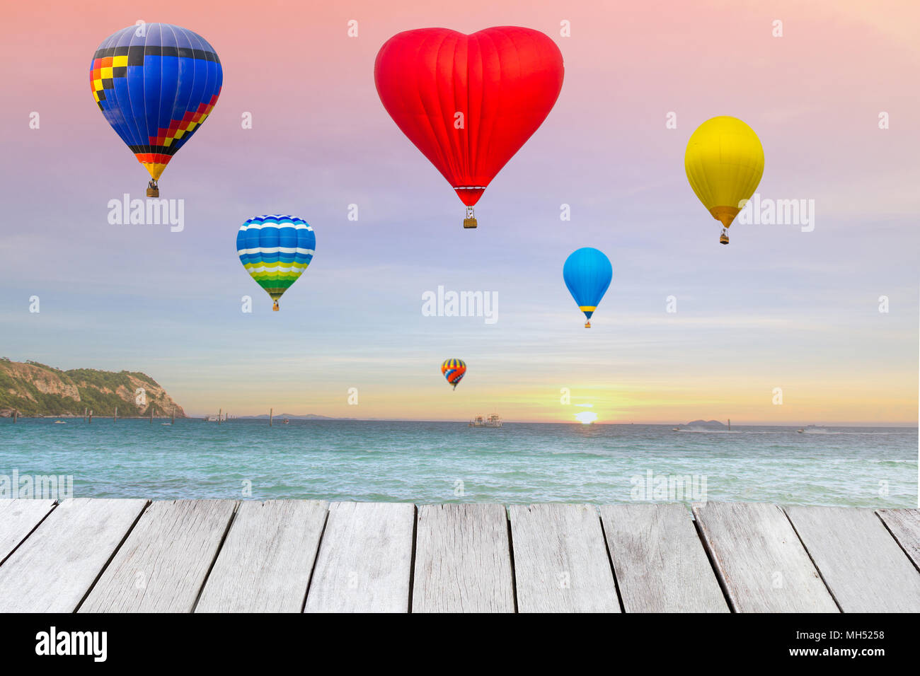 Balloons fly on the sea at time sunset or sunrise and wooden plank with ...