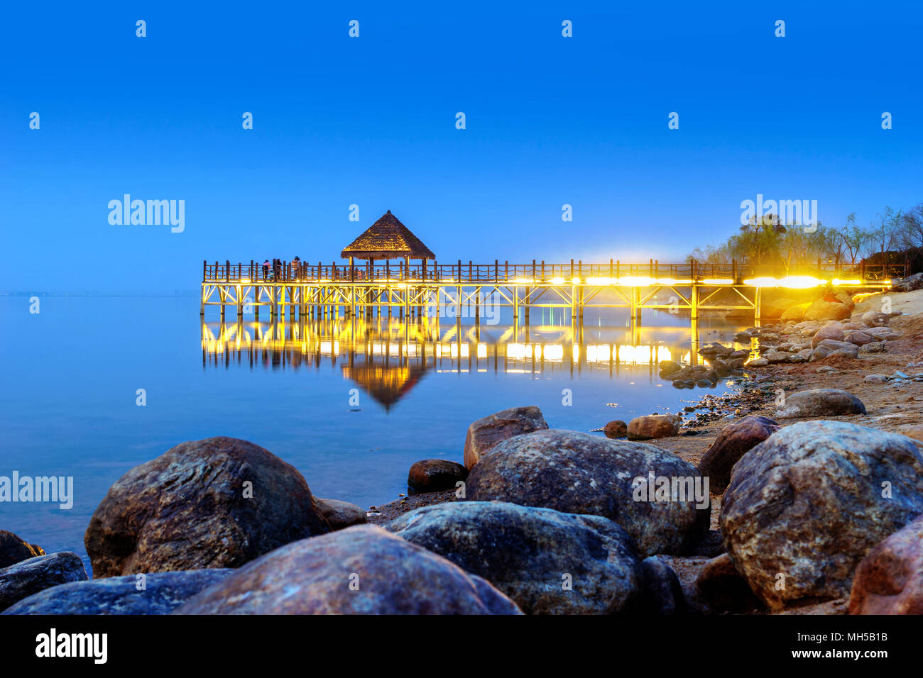 Tranquil lake and wooden trestle, evening landscape Stock Photo - Alamy