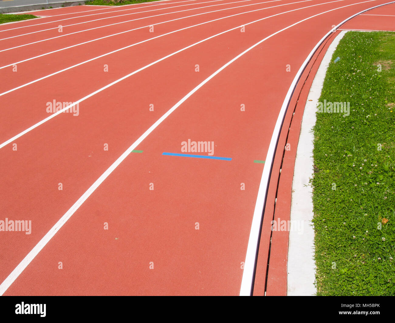 Bright red synthetic running track withe clear white lanes marked with ...