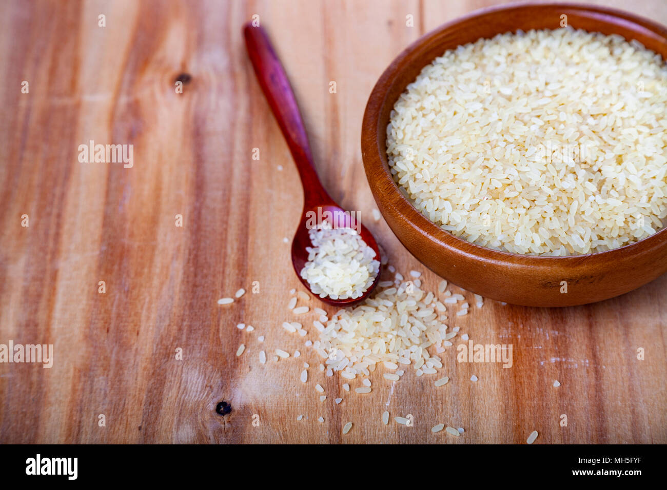 Raw steamed rice in a bowl and spoon on a wooden background. Ingredient ...