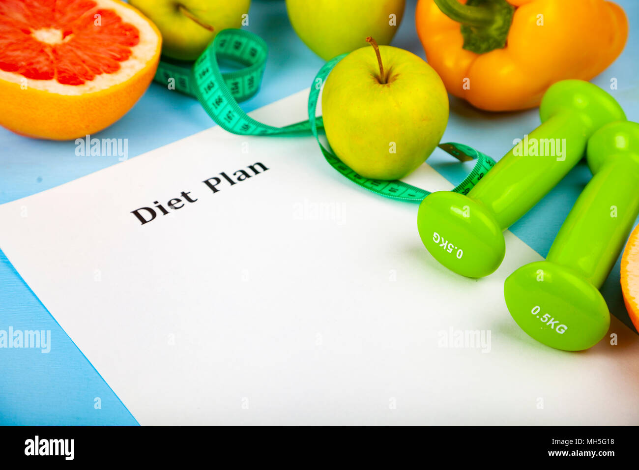 Food and sheet of paper with a diet plan on a blue wooden background ...