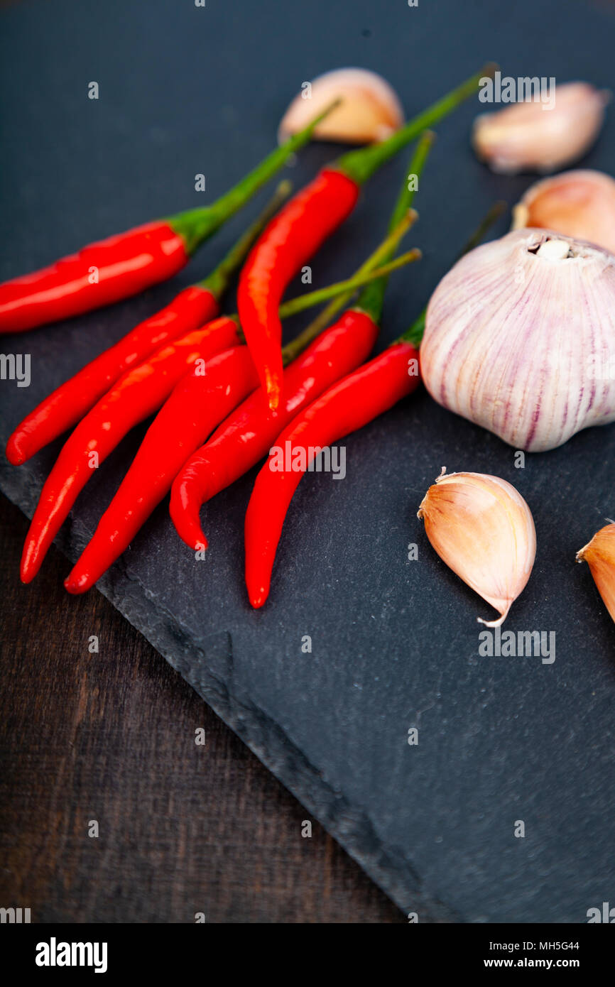 Red chili pepper, garlic and hot peppercorns on a dark background ...