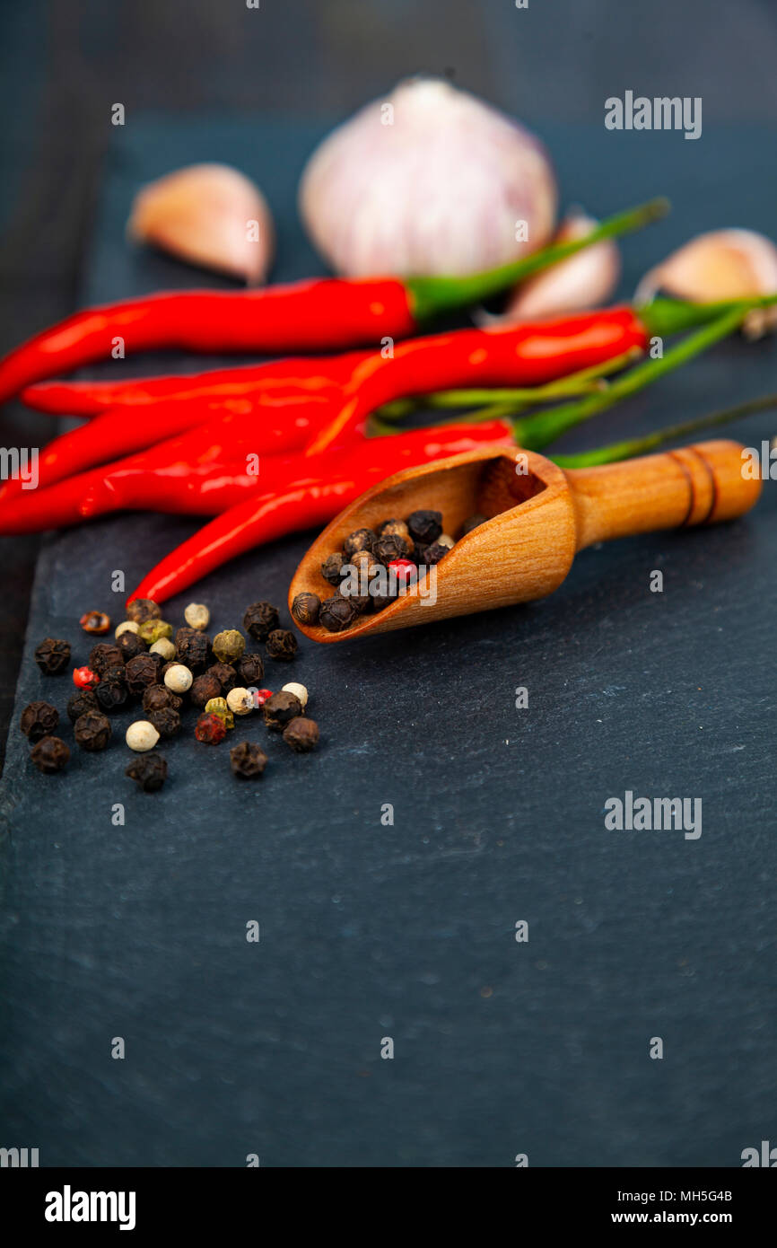 Red chili pepper, garlic and hot peppercorns on a dark background ...