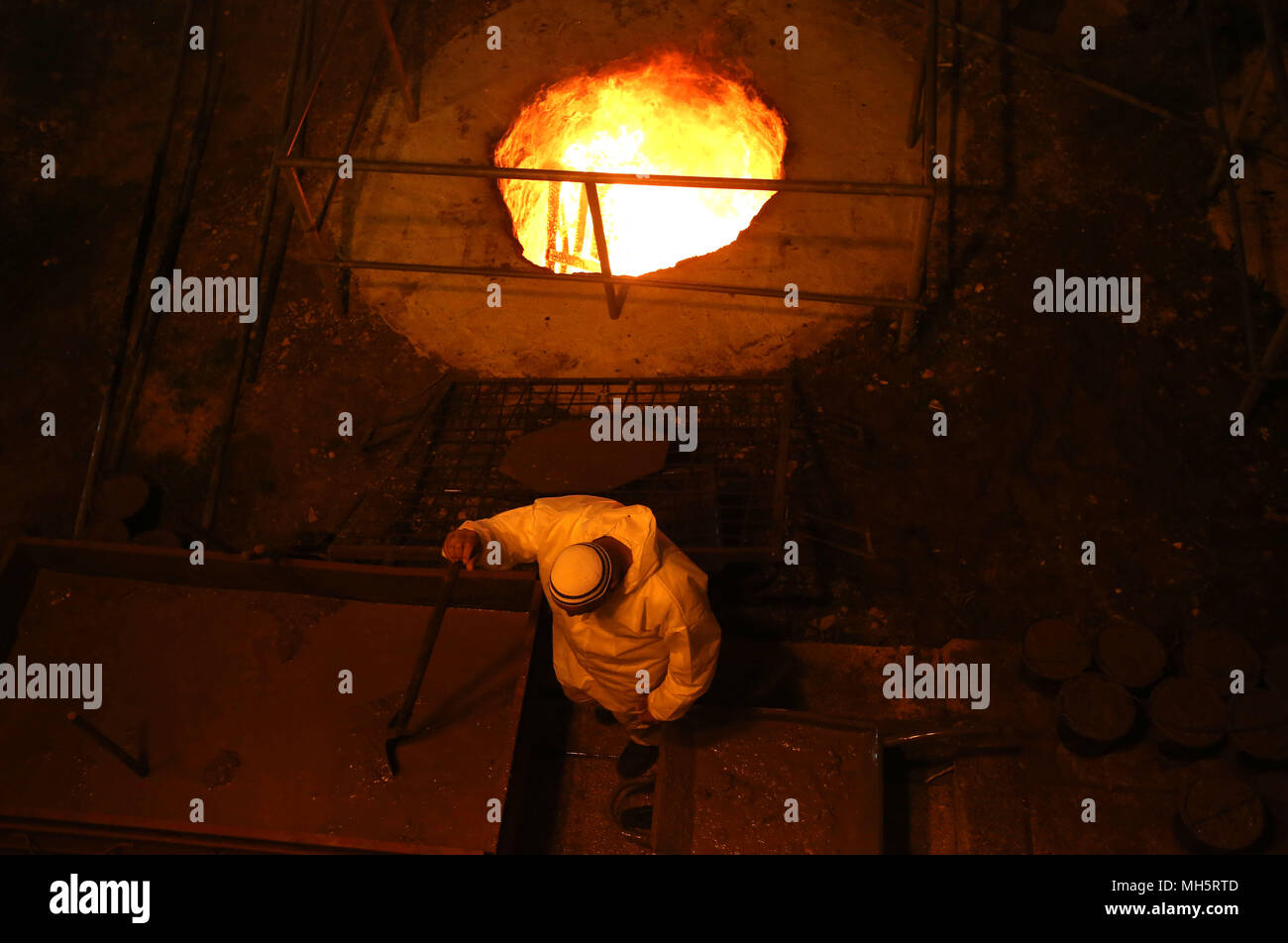 A member of the Samaritan community prepares blazing fire pits to cook ...