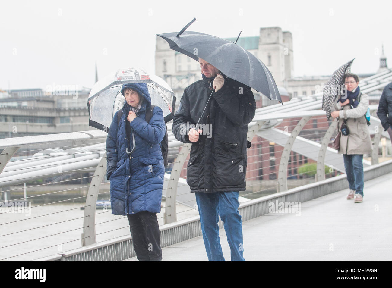 London UK. 30th April 2018. Pedestrians brave the freezing cold lashing ...