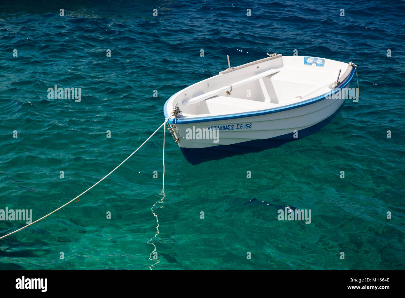 small Greek fishing boat floating in turquoise water Stock Photo - Alamy