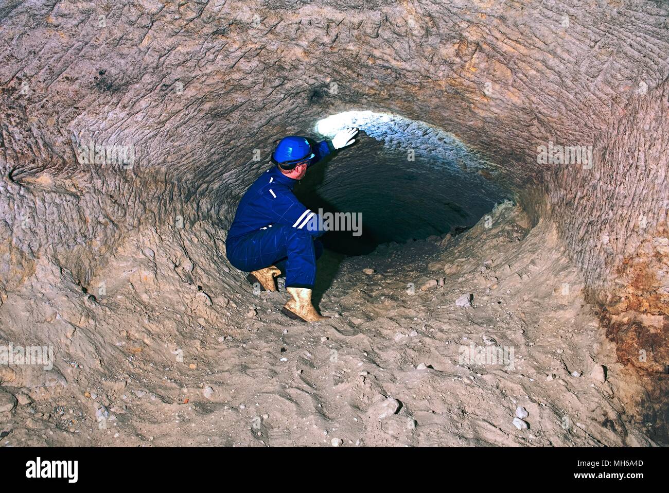 Staff do job in natural underground dome. Man with the illuminated ...