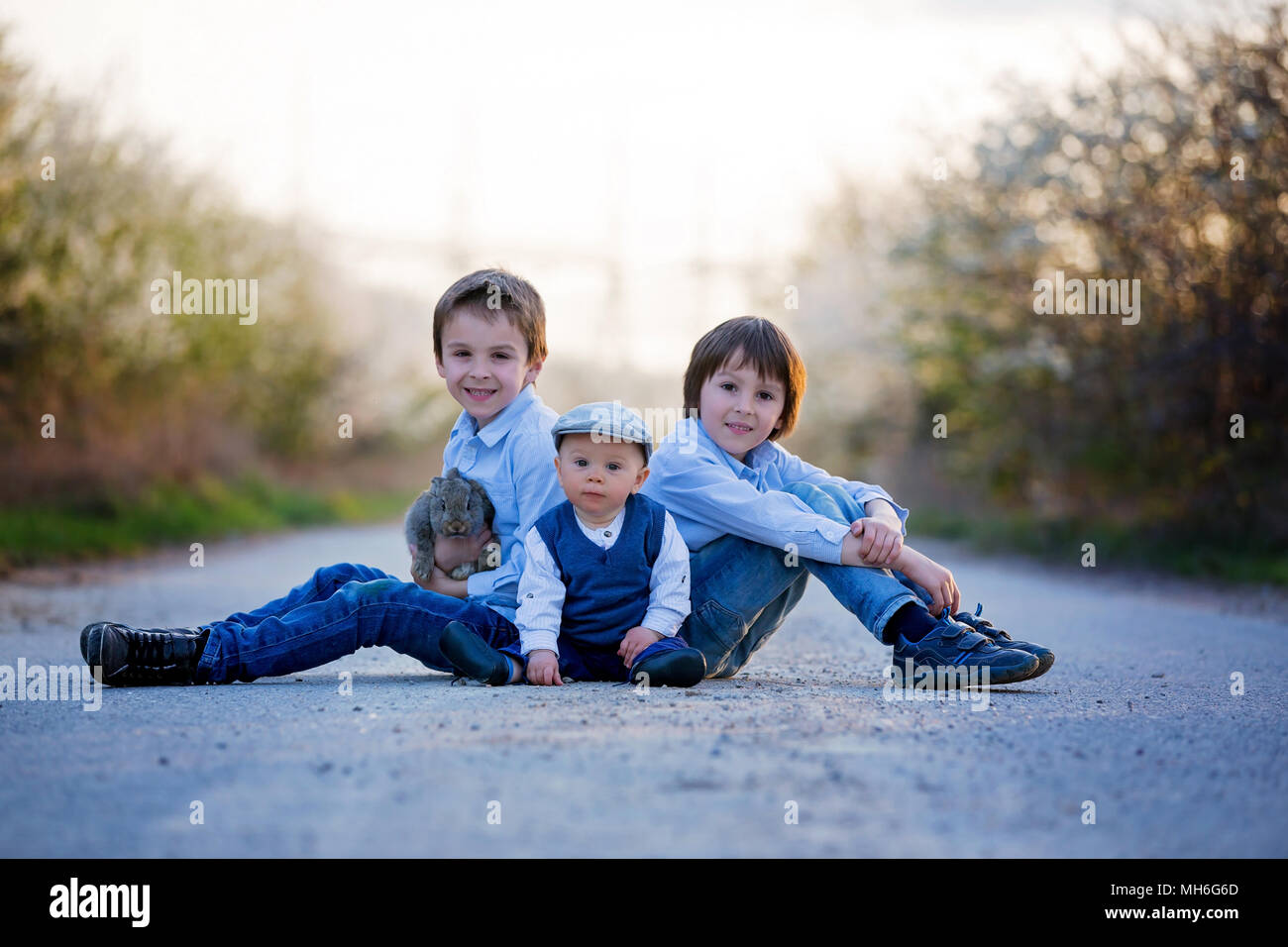Three children, boy brothers in park, playing with little bunnies on ...