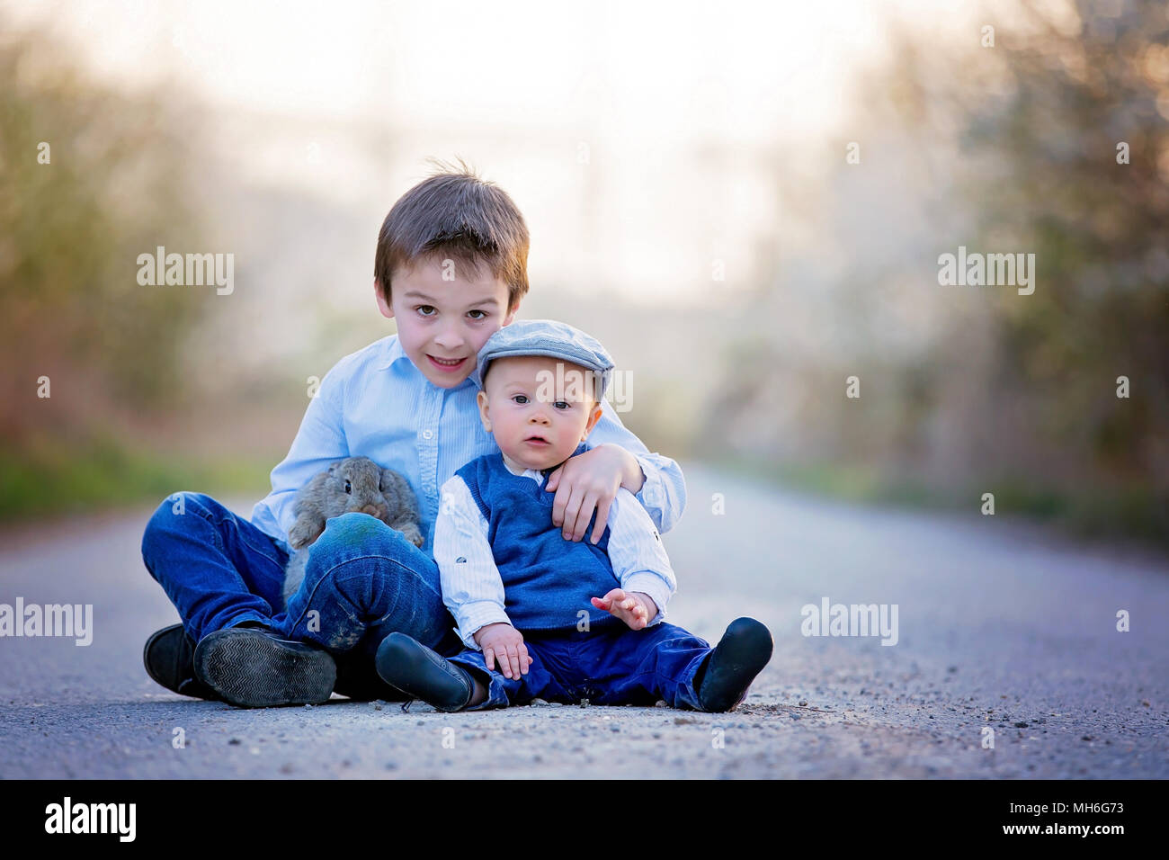 Three children, boy brothers in park, playing with little bunnies on ...