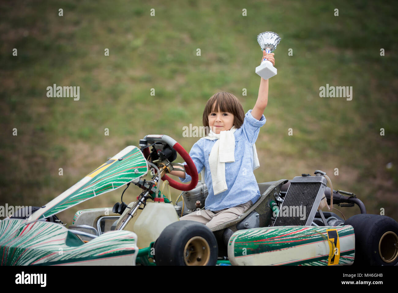 Cute child, riding go cart, wins champion cup, happiness winner concept ...