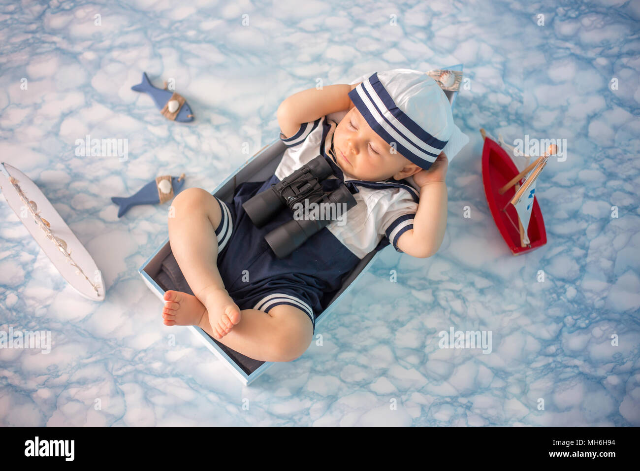 Cute toddler baby boy sleeping in wooden boat with fishes, starfish and ...