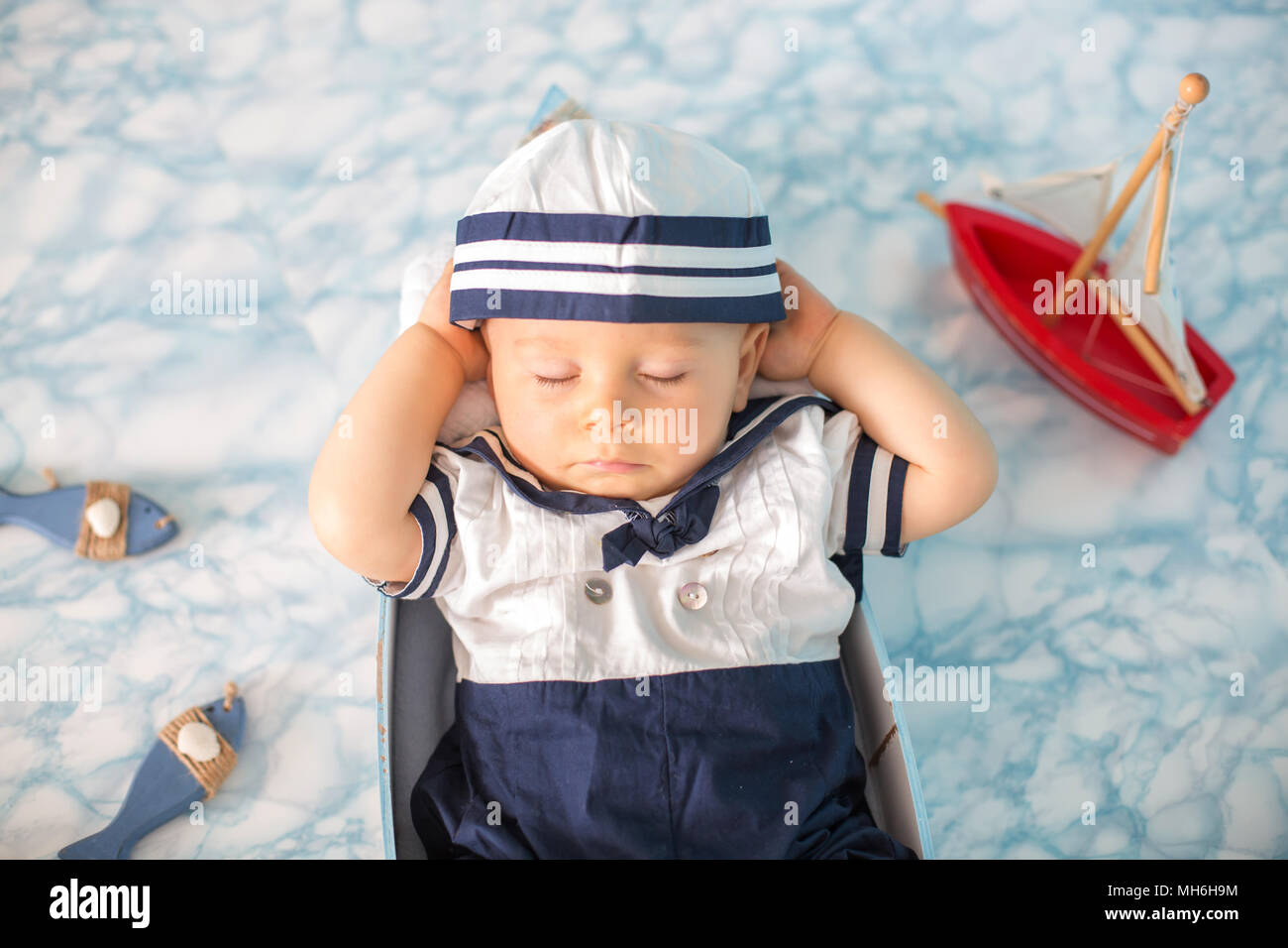 Cute toddler baby boy sleeping in wooden boat with fishes, starfish and ...