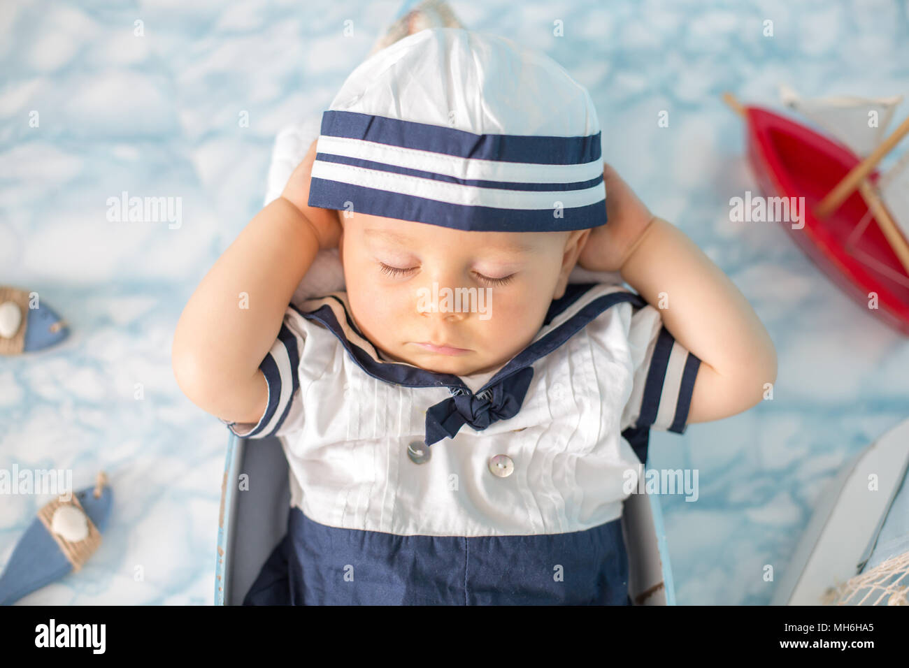 Cute toddler baby boy sleeping in wooden boat with fishes, starfish and ...