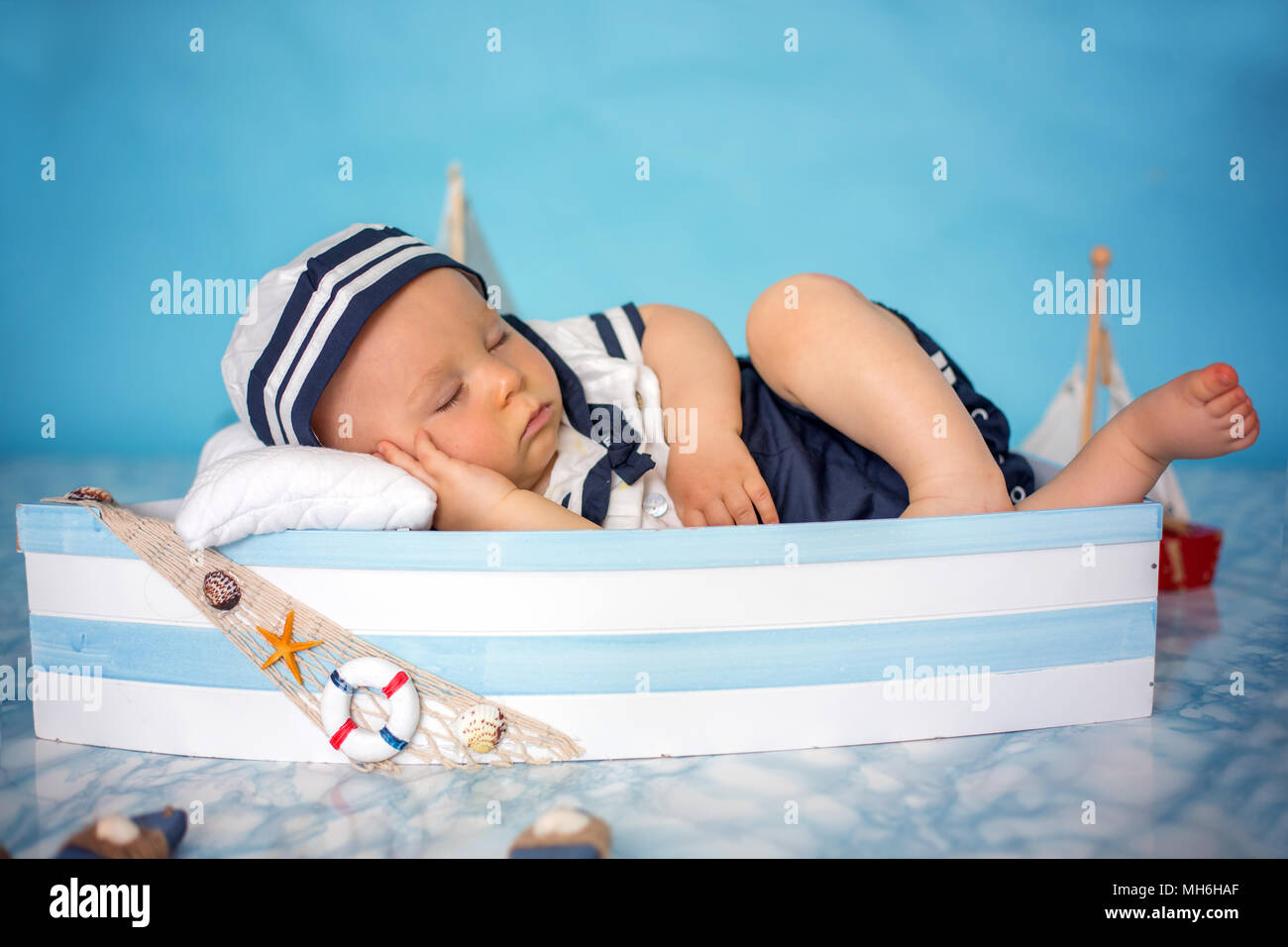 Cute toddler baby boy sleeping in wooden boat with fishes, starfish and ...