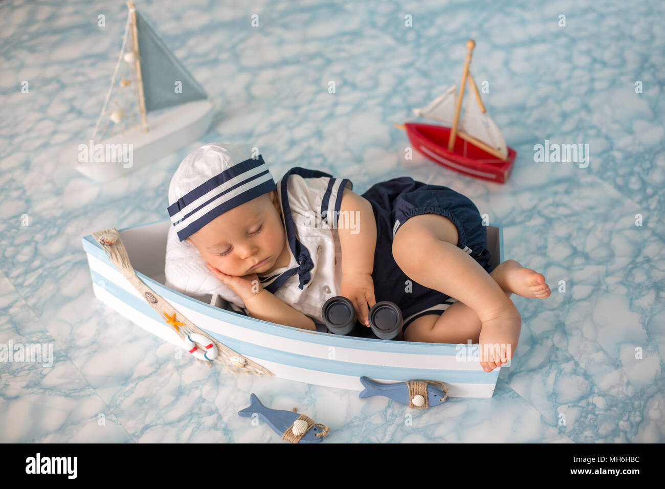 Cute toddler baby boy sleeping in wooden boat with fishes, starfish and ...