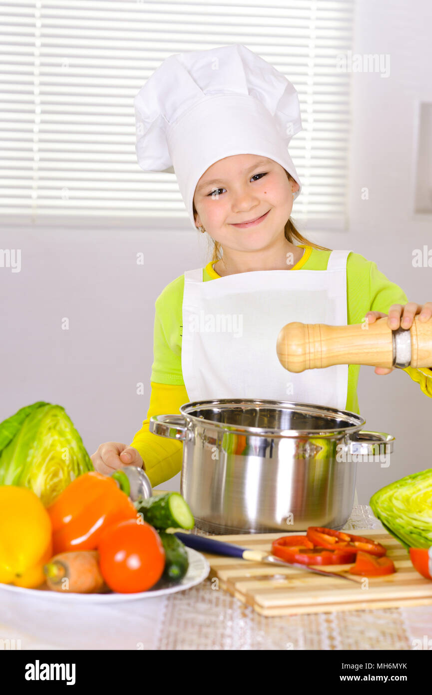 girl wearing chef uniform cooking on kitchen adding salt to dish Stock ...