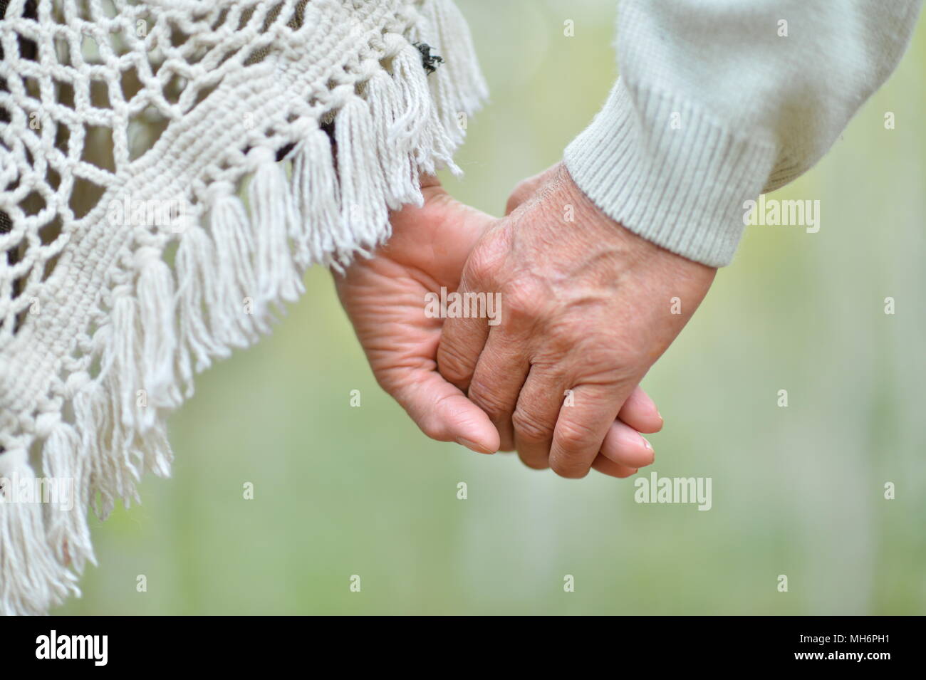 Elderly couple holding hands Stock Photo - Alamy