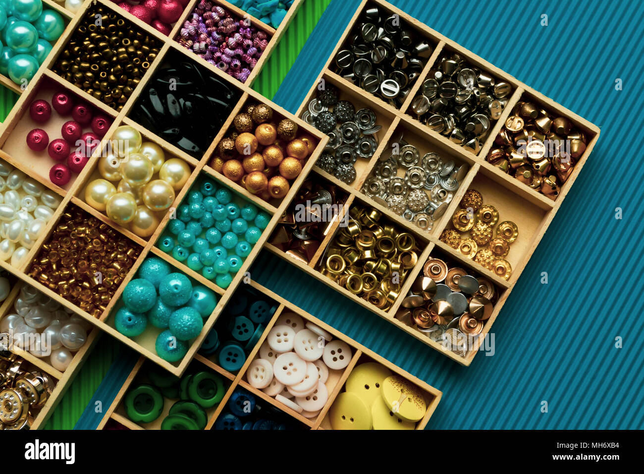 Different clothes buttons in wooden boxes on green and blue cardboard ...