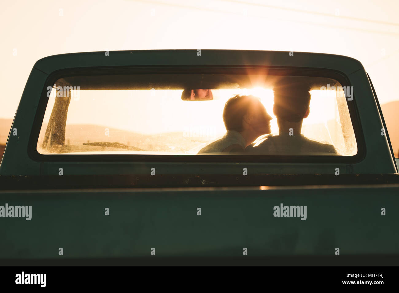 Rear view of couple sitting inside their pick up truck. Woman trying to ...