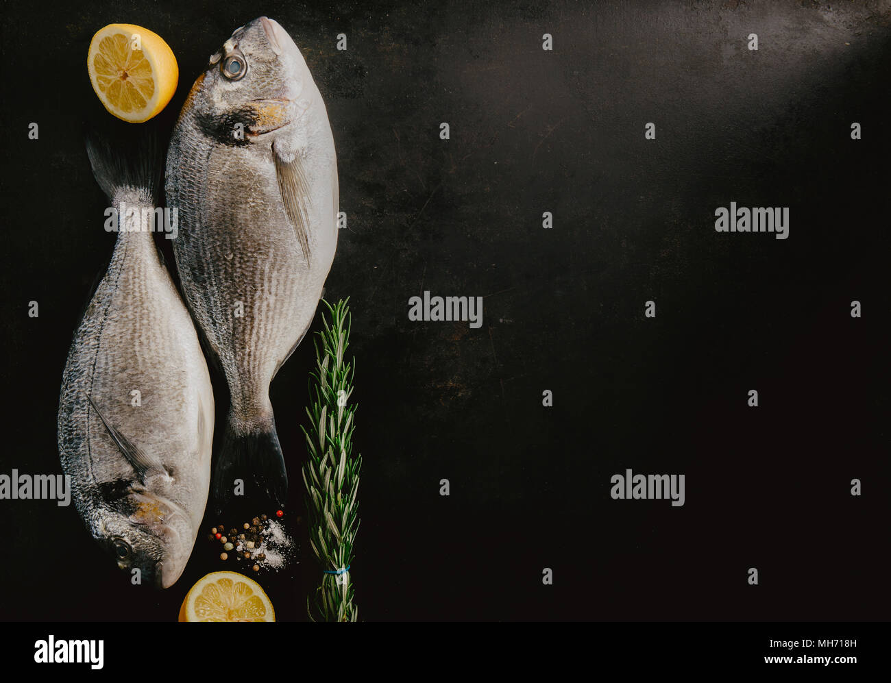 Top view of fish on rough board with spices and different vegetables ...