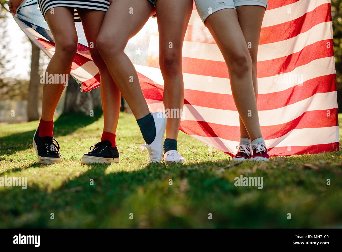 Low section of three young women standing outdoors with USA national ...