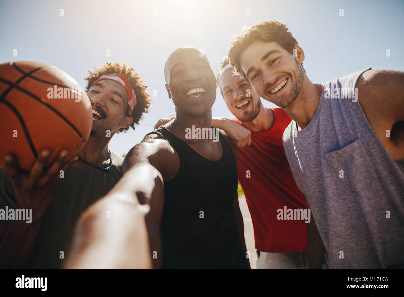 Four men posing for selfie holding a basketball. Men enjoying while ...
