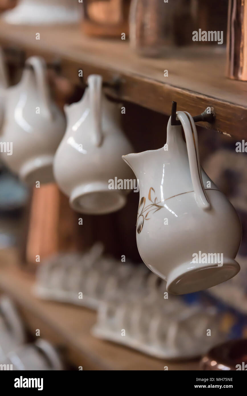 Old Victorian creamer jugs hanging od wooden rack in mansion kitchen ...