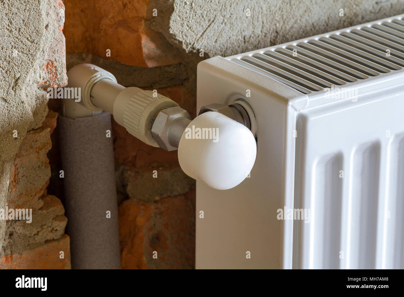 Close-up side view of isolated installed heating radiator on brick ...