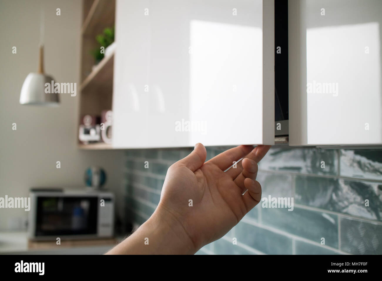 Kitchen interior with modern furniture. The man opens a modern hanging ...